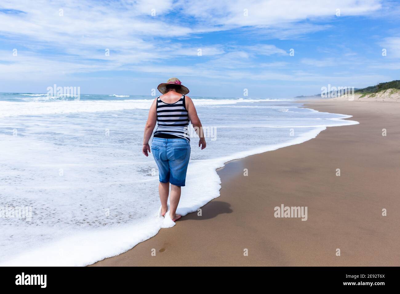 Caucasian Mature woman holidays walking beach ocean shoreline with wave ...