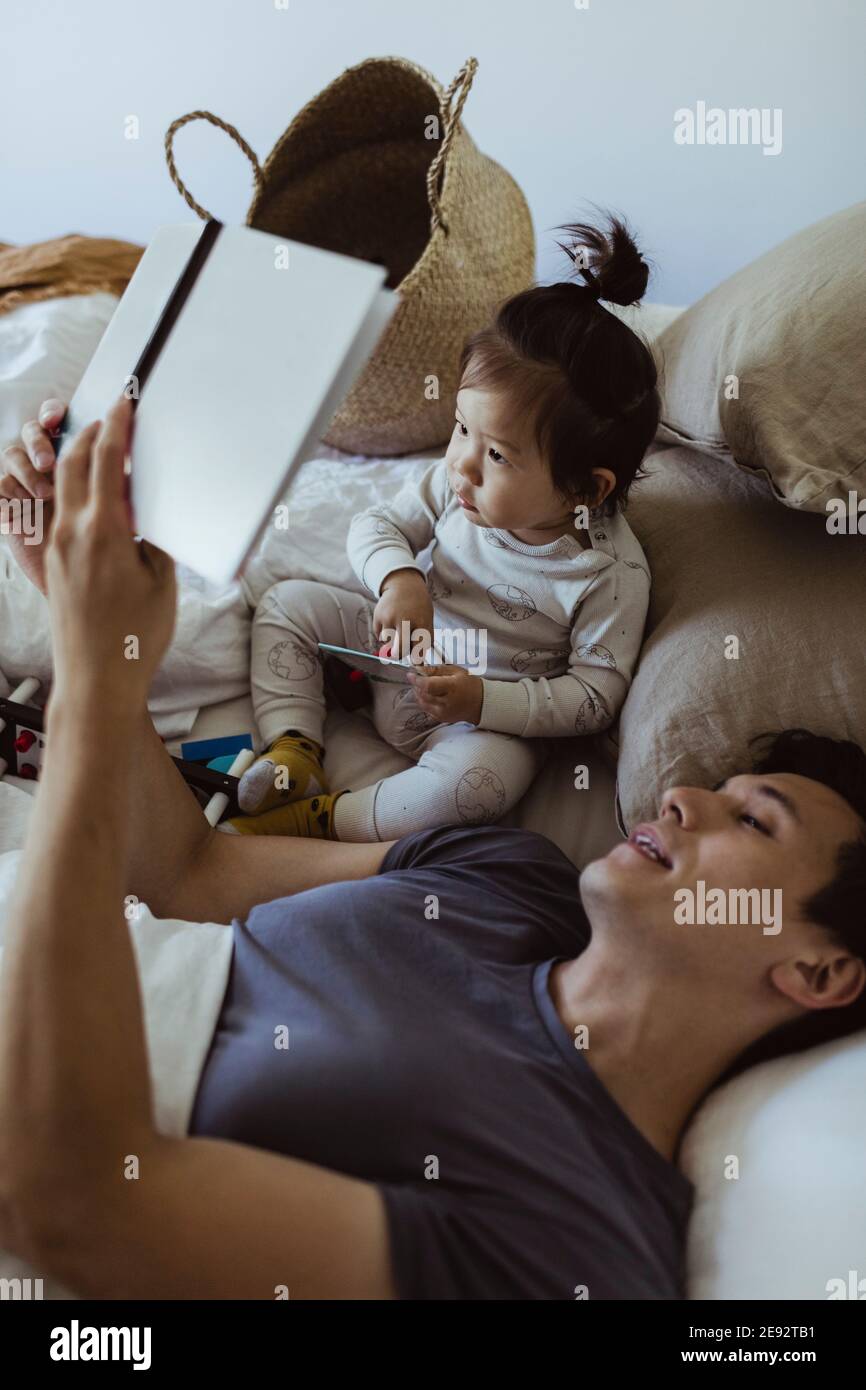 High angel view of father reading book with son in bedroom Stock Photo ...