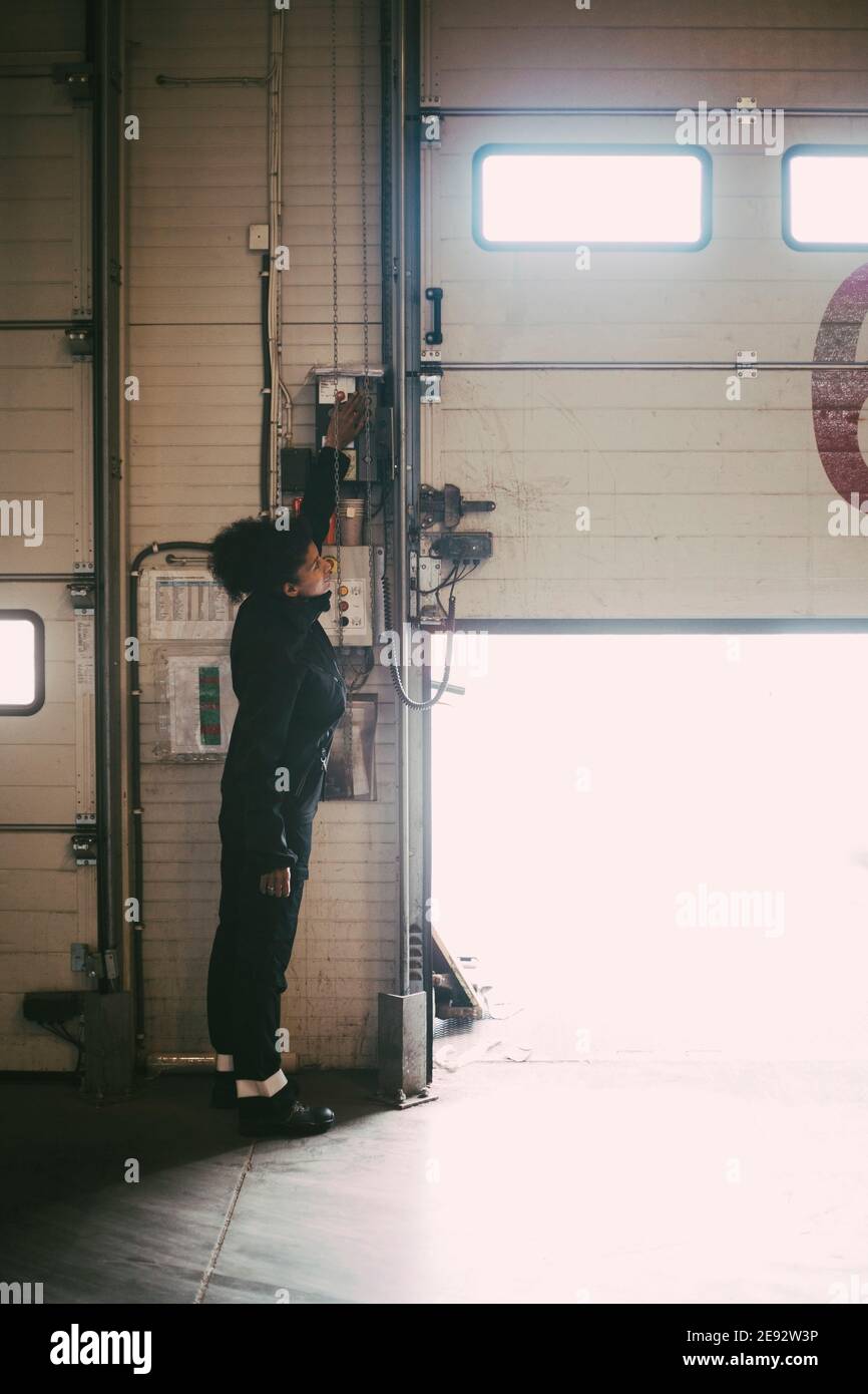 Female worker opening shutter of distribution warehouse Stock Photo - Alamy