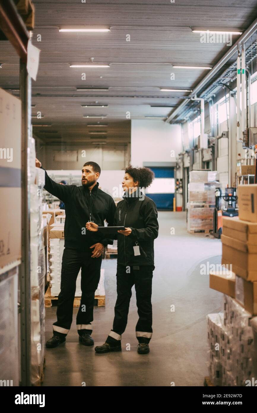 Female and male colleagues examining at distribution warehouse Stock ...