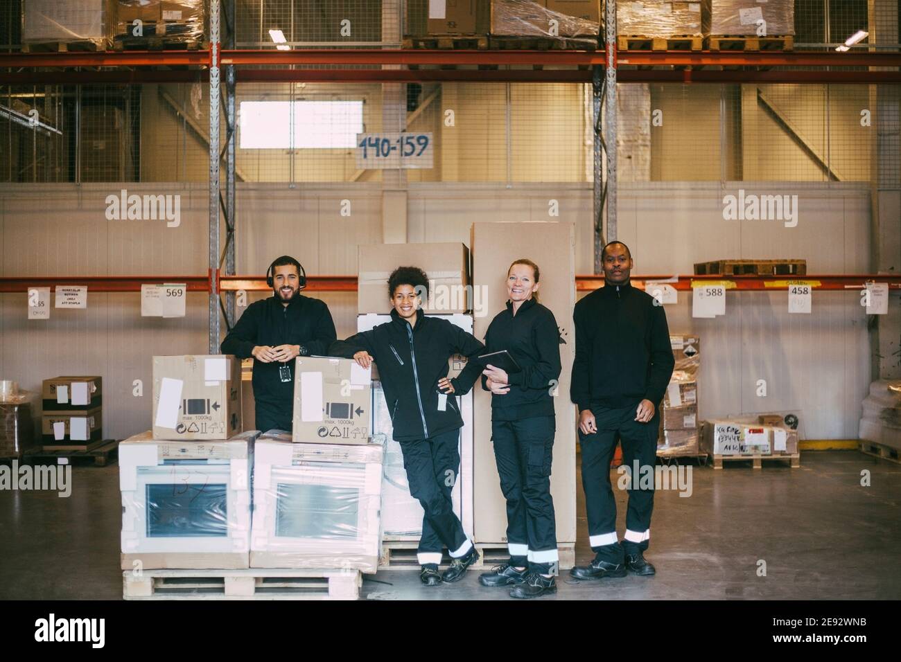 Portrait of smiling warehouse workers standing with box containers ... Portrait of smiling warehouse workers standing with box containers ...