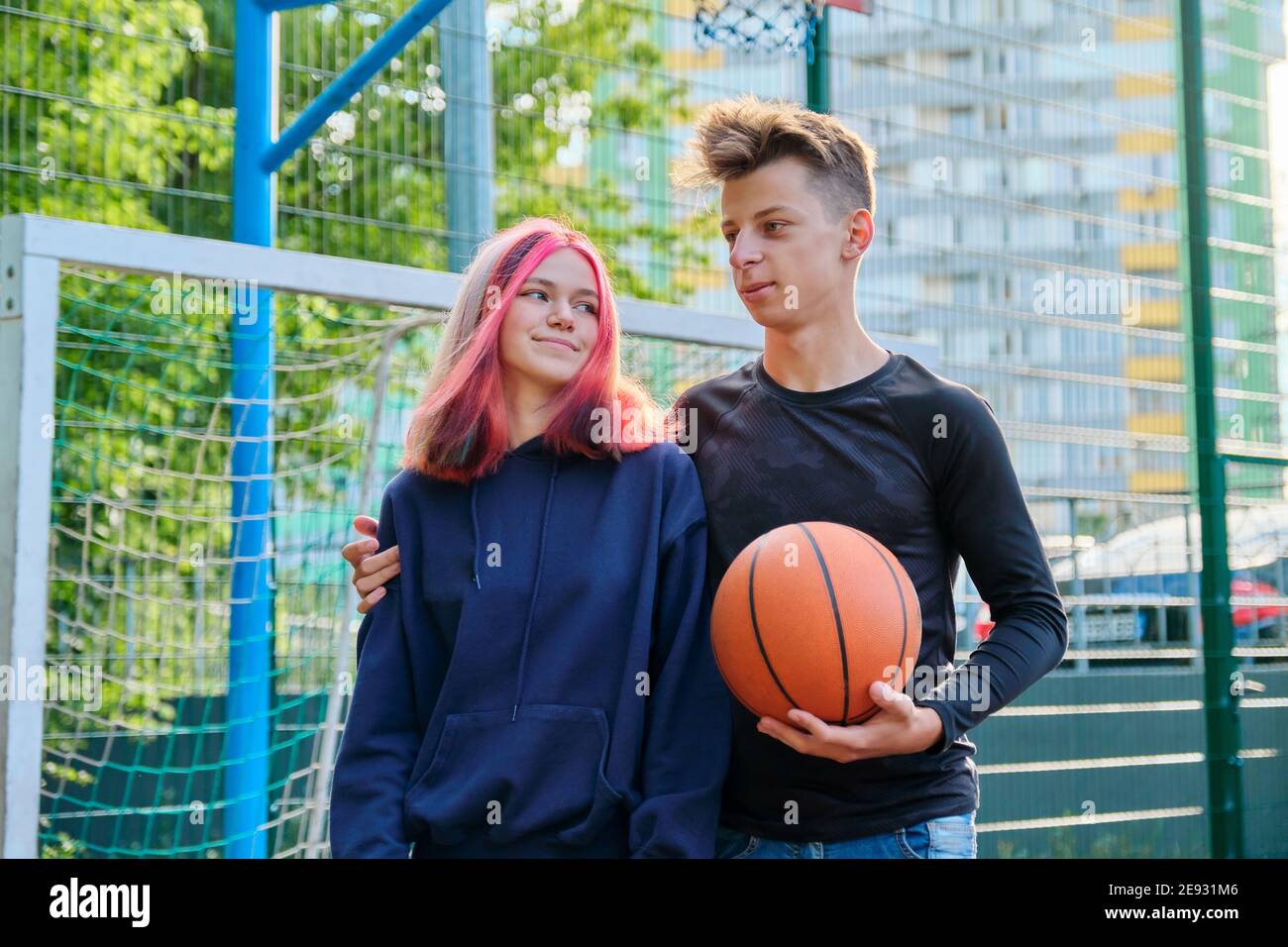 Portrait of guy and teenage girl hugging on basketball court with ball ...