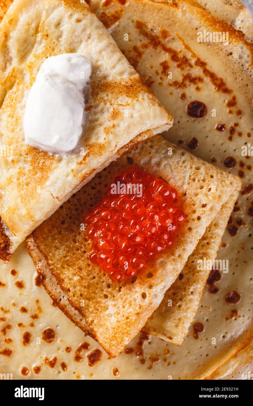 Traditional Russian Crepes Blini stacked in a plate with red caviar ...
