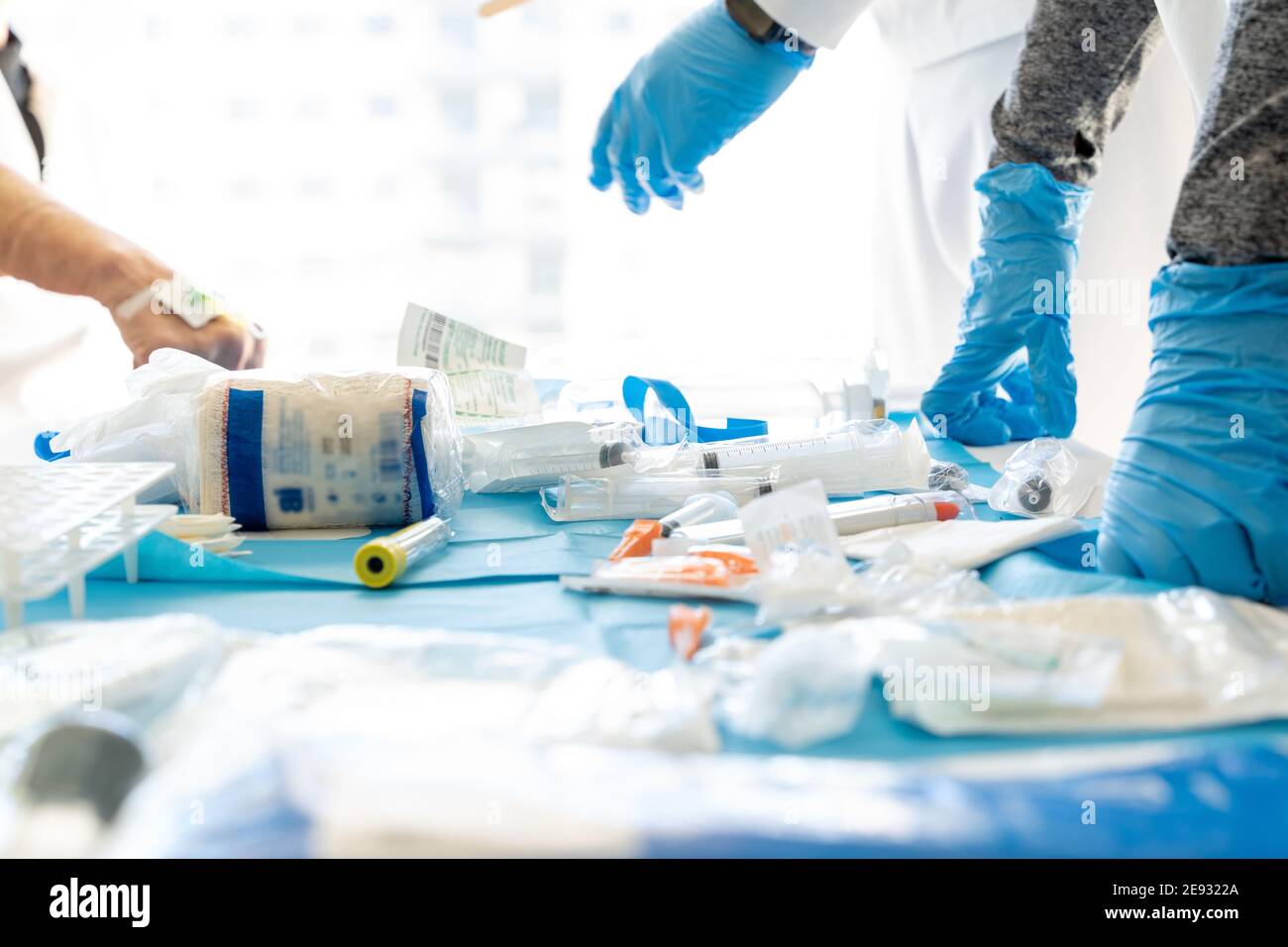 Crop anonymous doctors in protective gloves and patient at table with ...