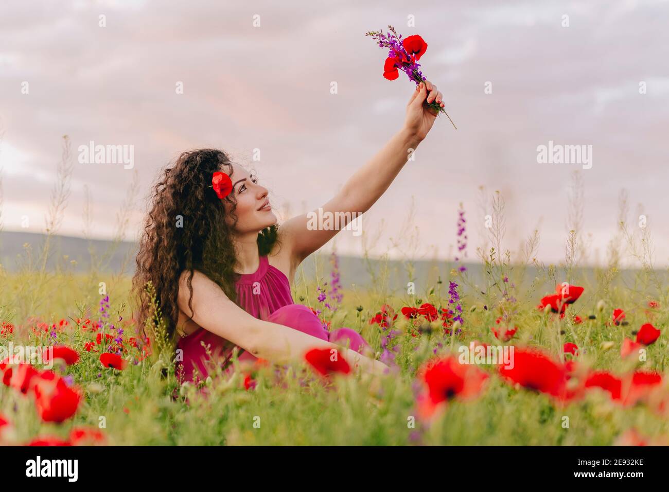 Young adorable girl wearing poppy in her hair and holding a bunch of ...