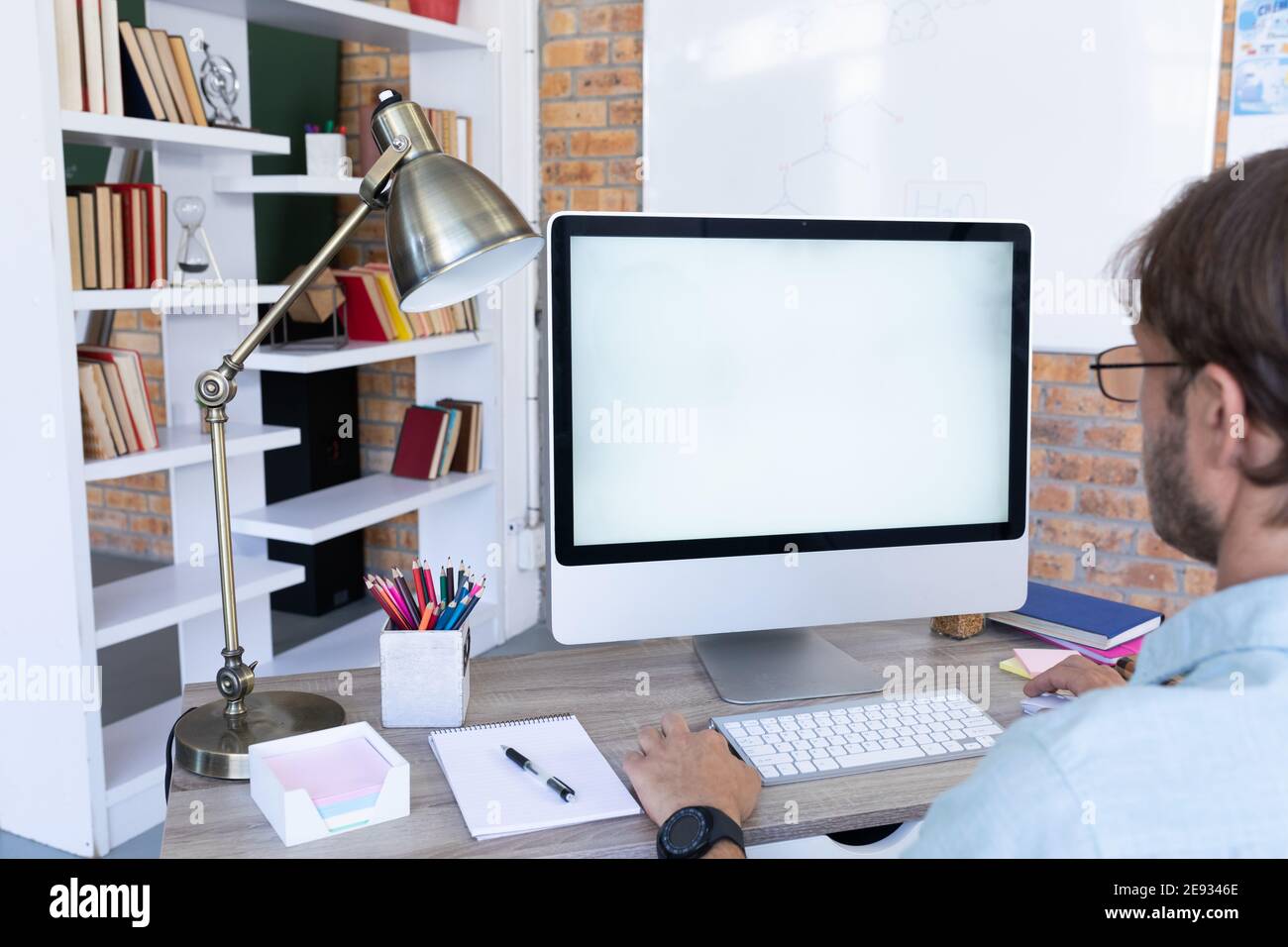 Over shoulder view of caucasian man sitting at desk making video call ...