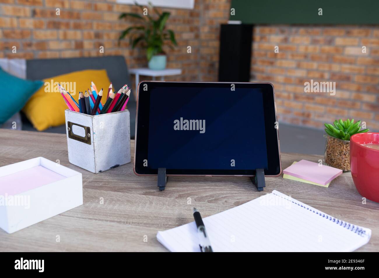 Creative workstation on desk with tablet computer on stand notebook and ...