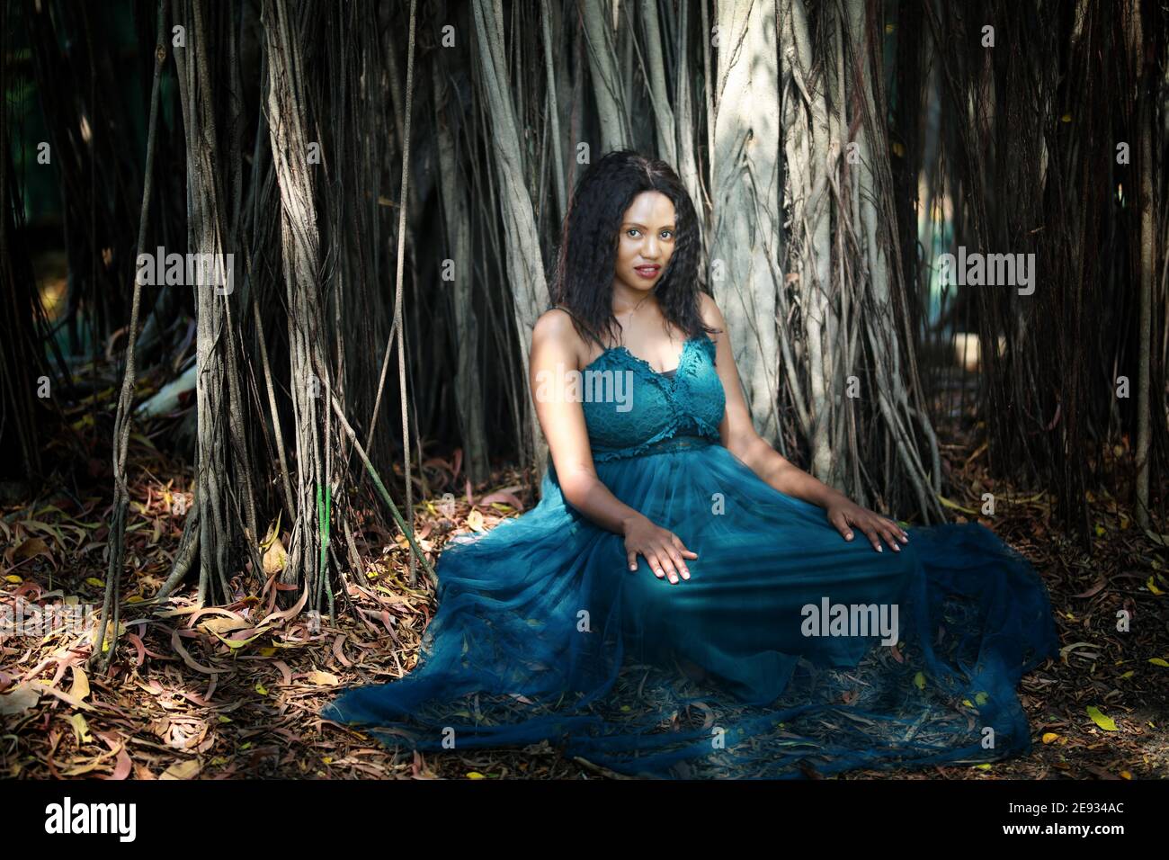 Cheerful young woman standing by tree in the jungle Stock Photo - Alamy