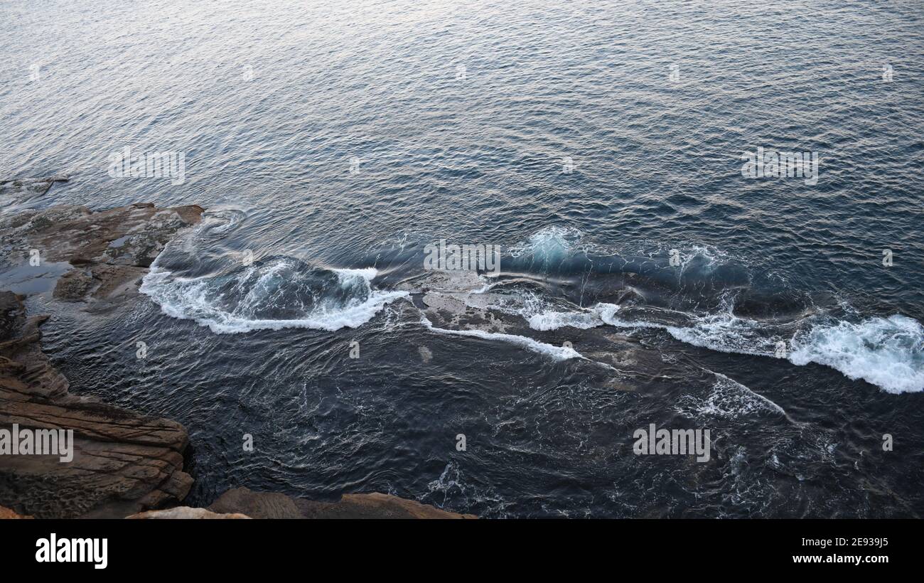 Aerial view of sea waves lash line impact rock on the beach in Sydney ...