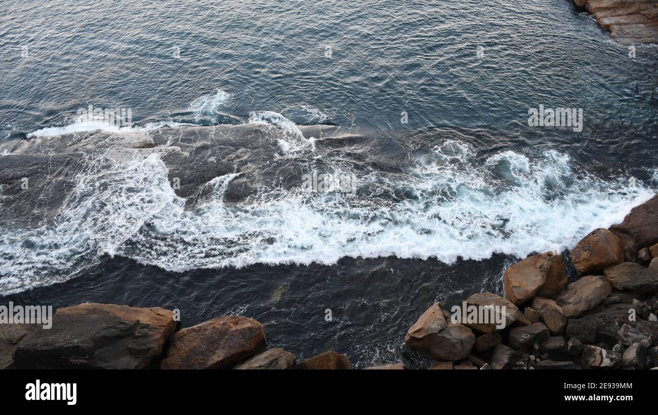 Aerial view of sea waves lash line impact rock on the beach in Sydney ...