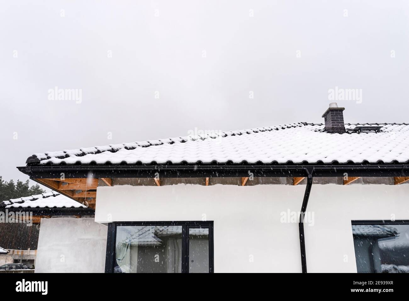 Single-family house roof covered with snow against a cloudy sky ...
