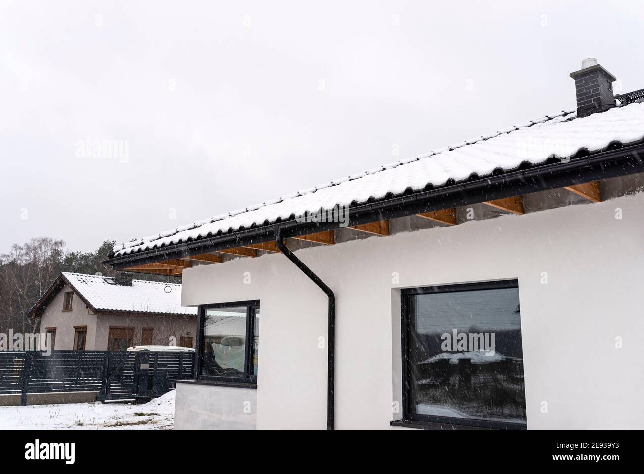 Single-family house roof covered with snow against a cloudy sky ...
