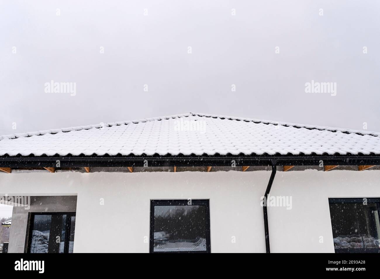 Single-family house roof covered with snow against a cloudy sky ...