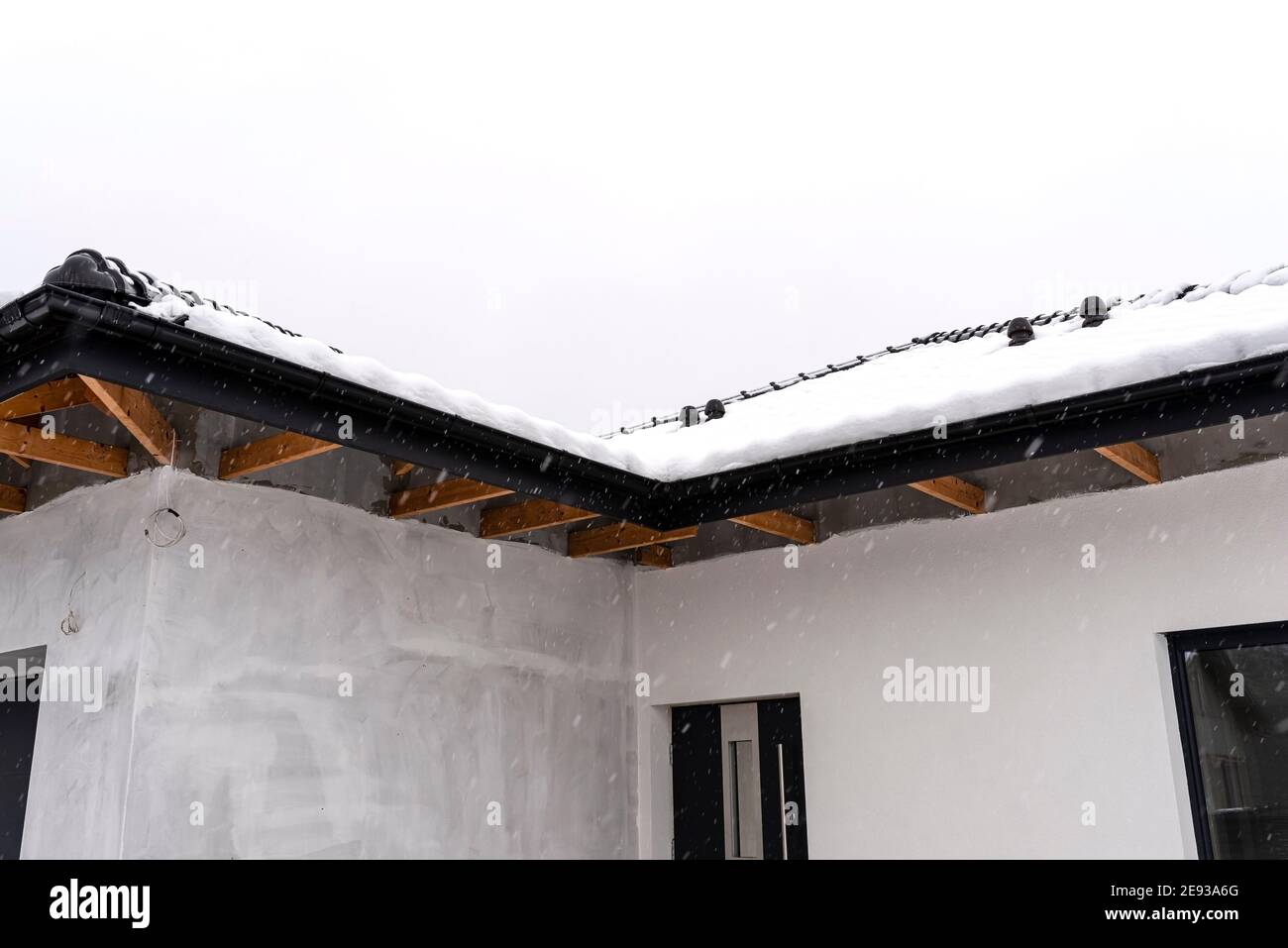 Single-family house roof covered with snow against a cloudy sky ...