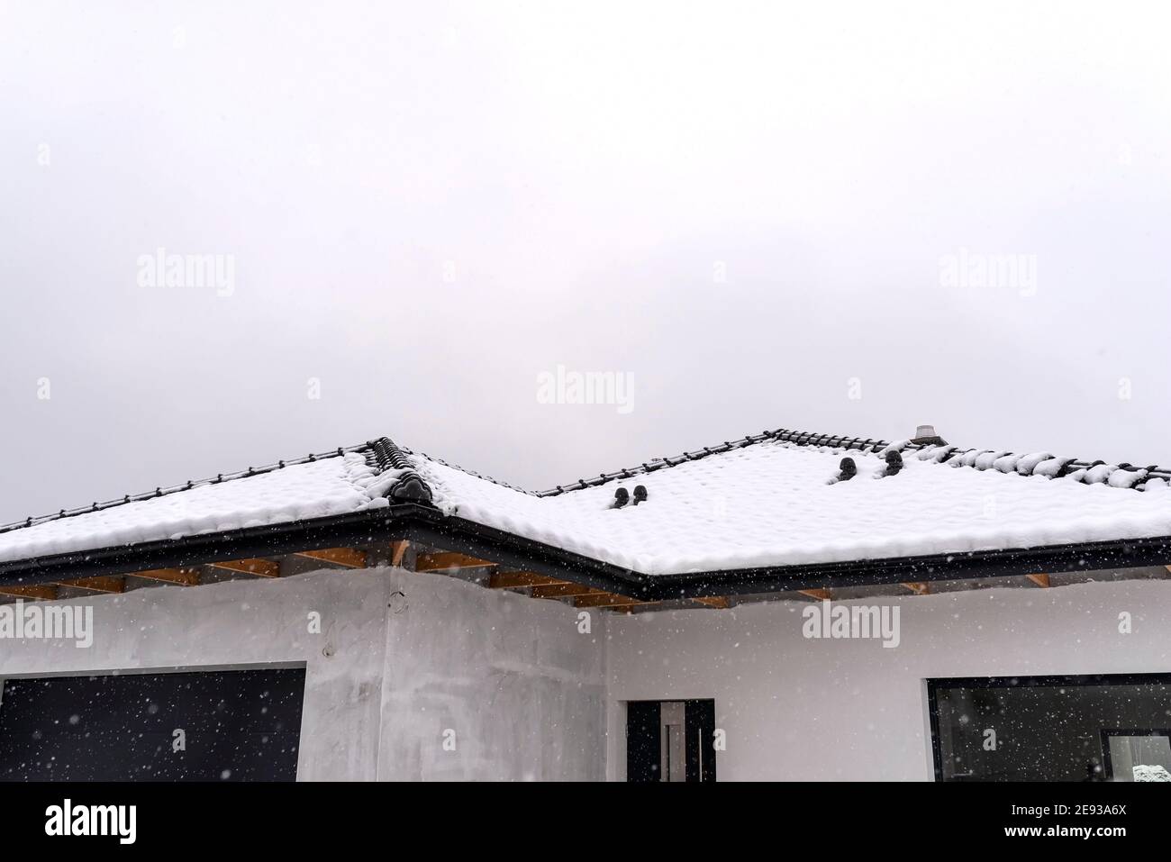 Single-family house roof covered with snow against a cloudy sky ...