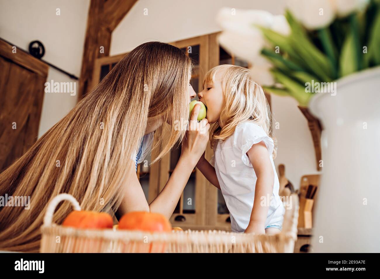 Little girl treats her mother to an apple at the kitchen Stock Photo ...