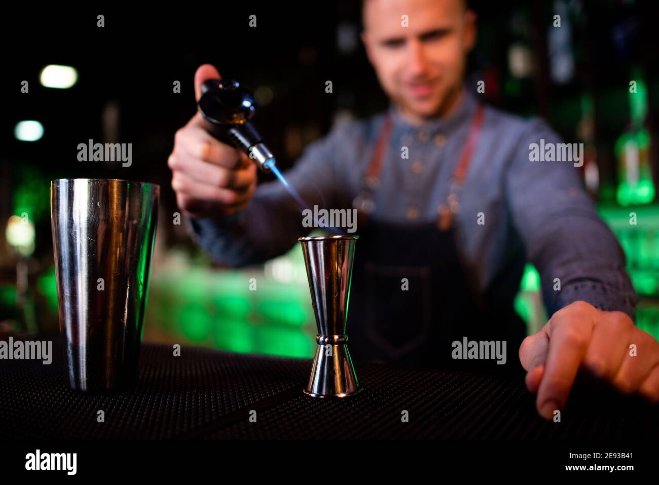 Young guy a working as a bartender while preparing cocktails in a pub ...