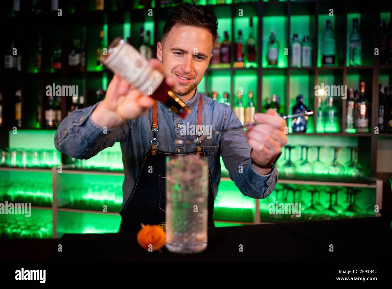 Young guy working as a bartender while preparing cocktails in a pub ...