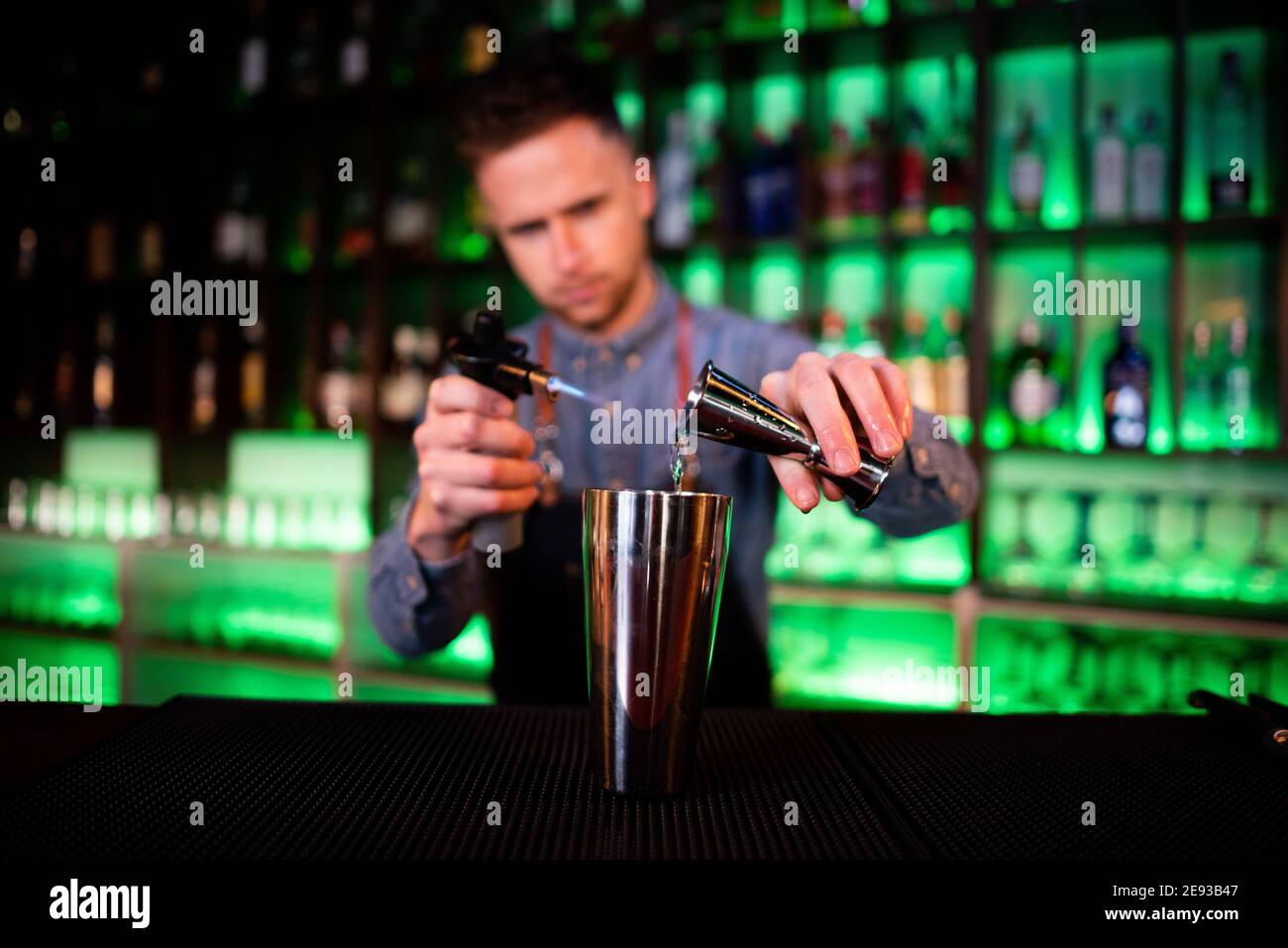 Young guy working as a bartender while preparing cocktails in a pub ...