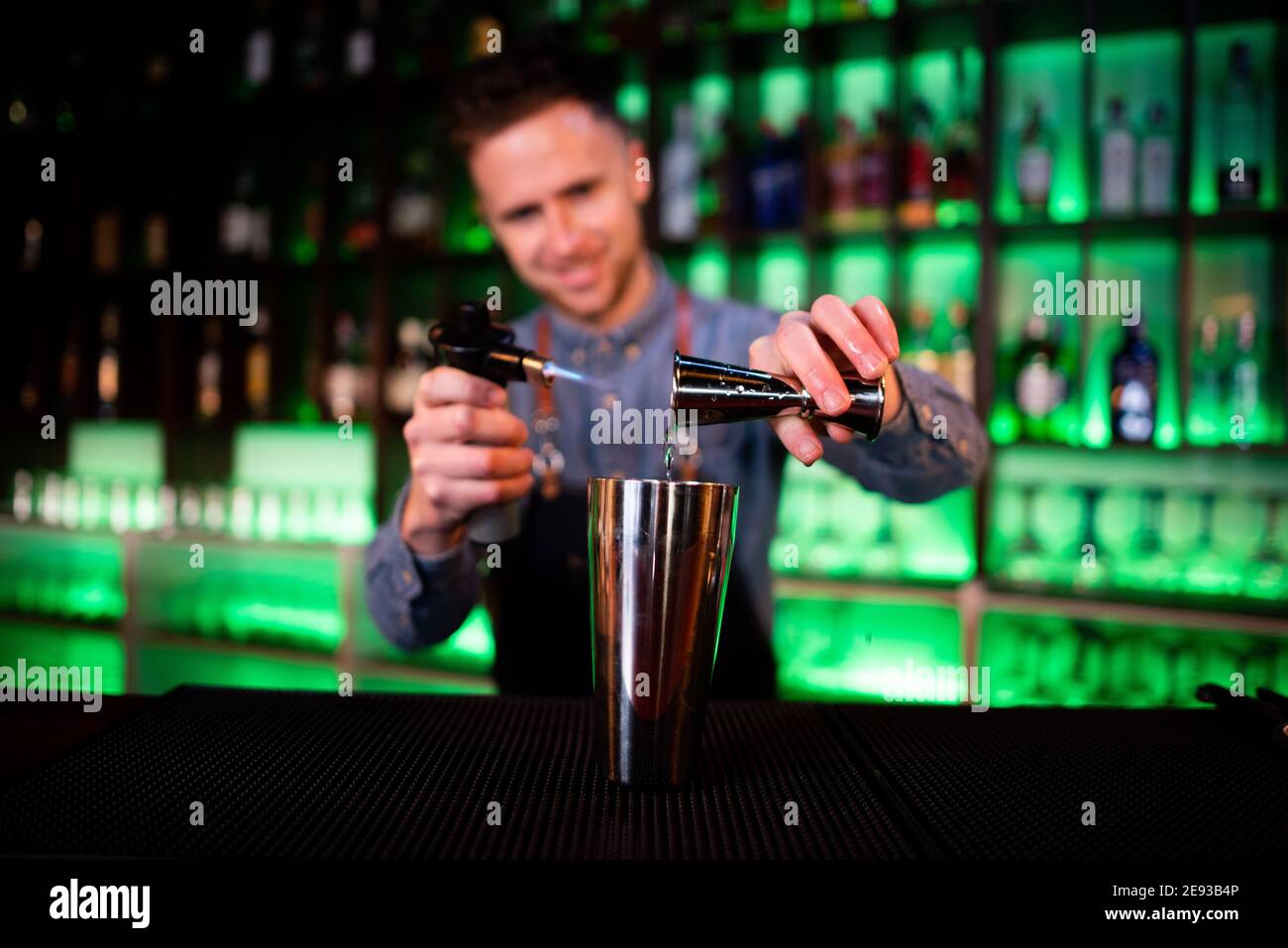 Young guy working as a bartender while preparing cocktails in a pub ...