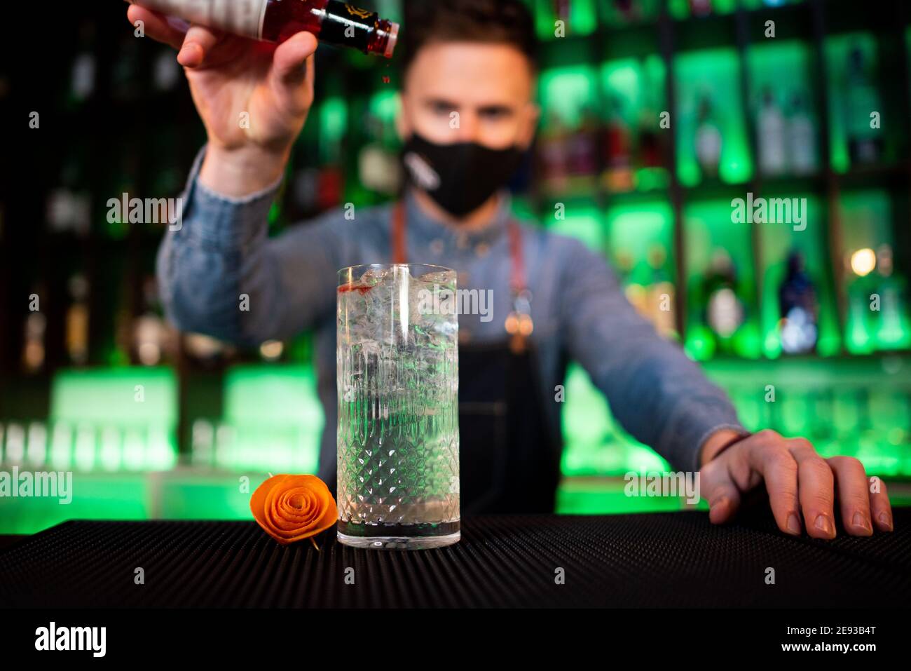 Young guy working as a bartender while preparing cocktails in a pub ...