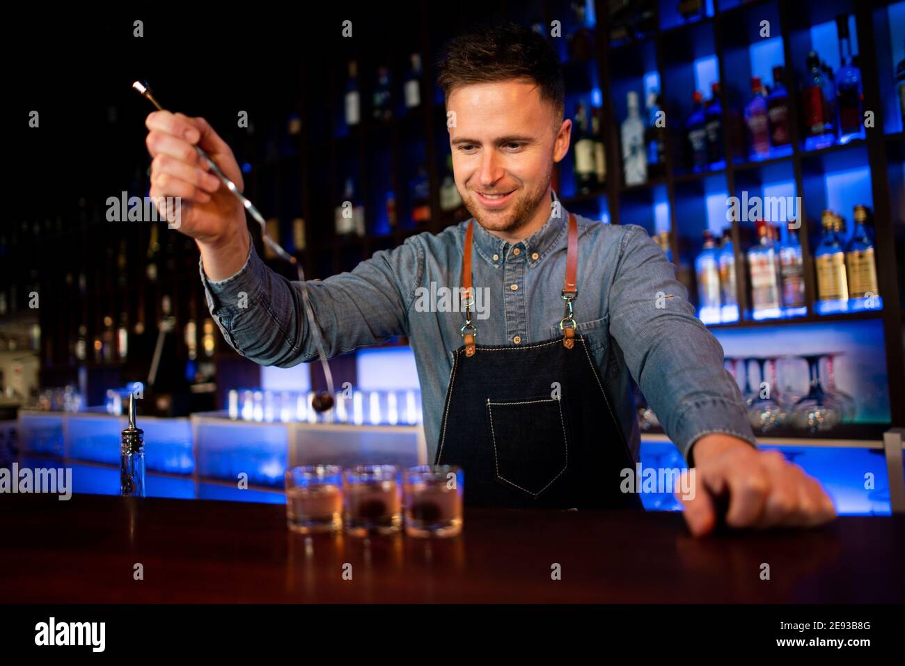 Young guy a working as a bartender while preparing cocktails in a pub ...