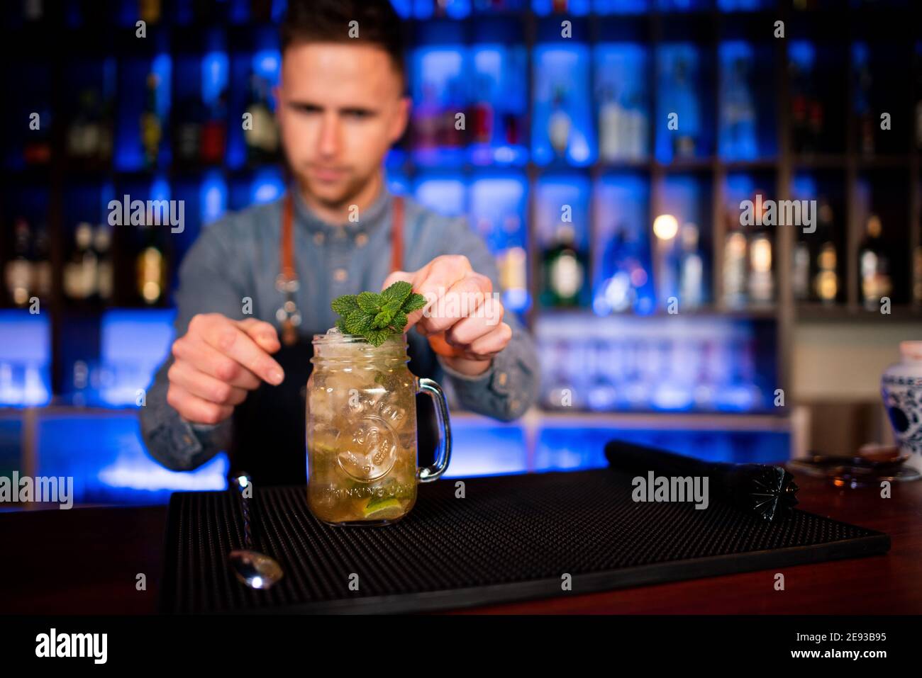 Young guy a working as a bartender while preparing cocktails in a pub ...