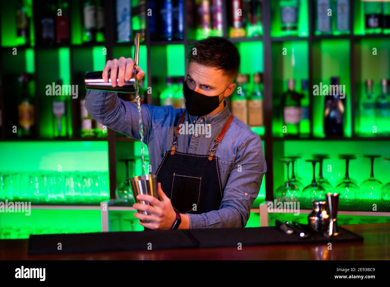 Young guy a working as a bartender while preparing cocktails in a pub ...