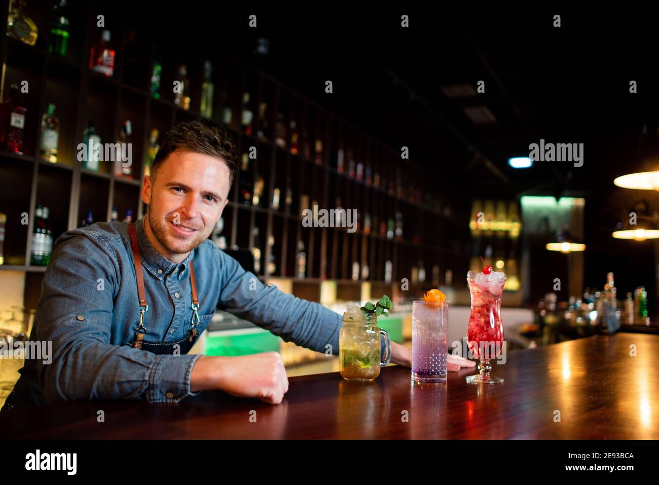 Young guy a working as a bartender while preparing cocktails in a pub ...