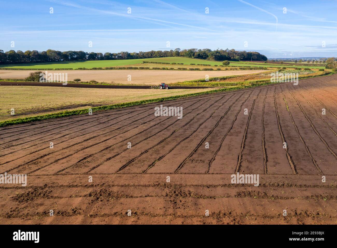 elevated view of red tractor ploughing a field with prepared field in ...
