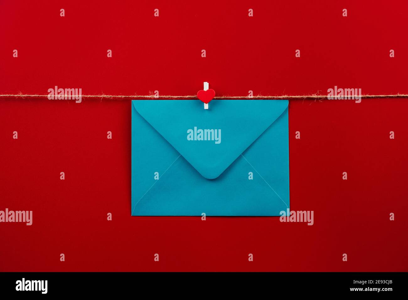 One closed blue envelope with a clothespin with a heart hanging on rope ...