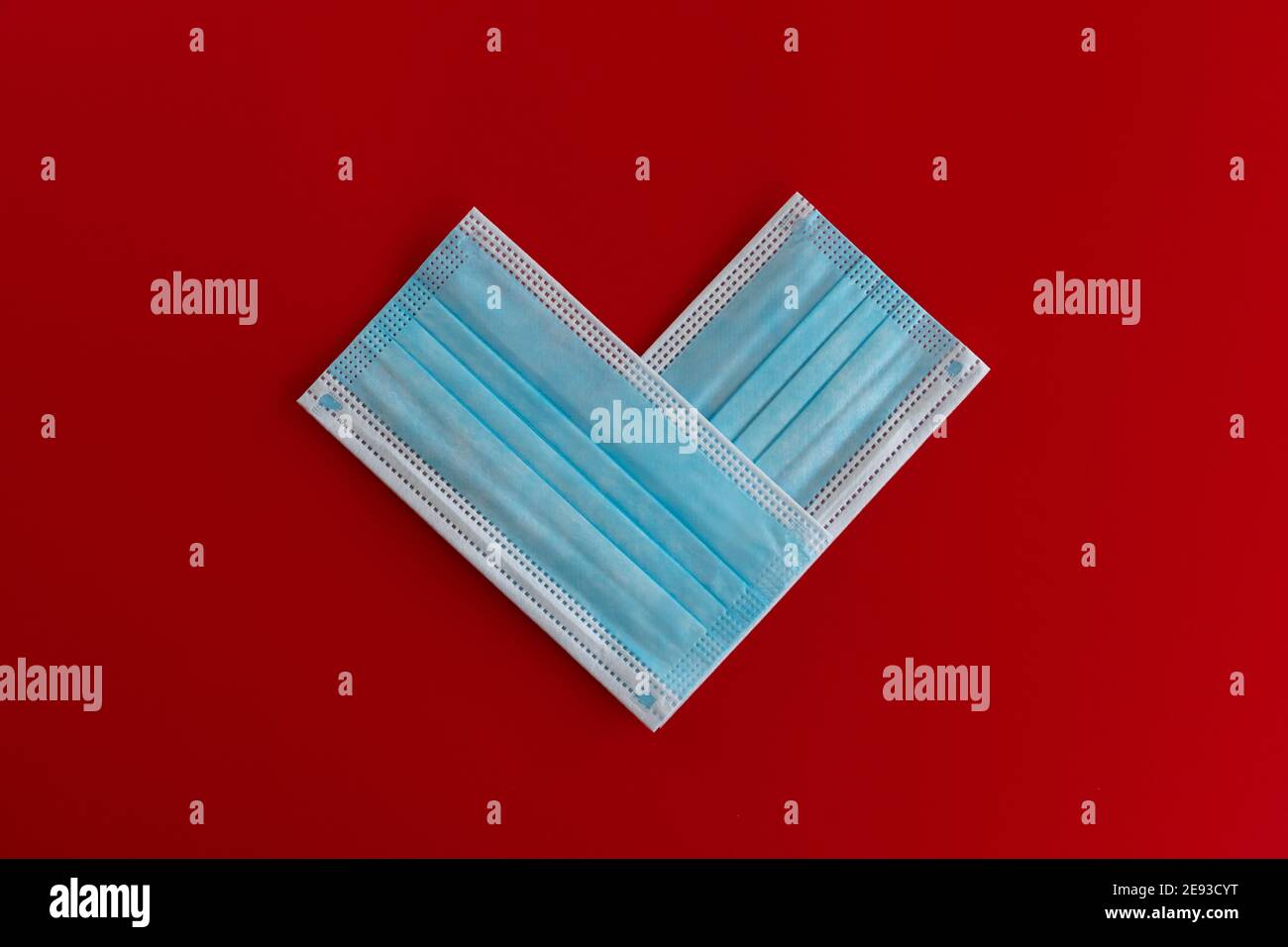 Two close-up blue medical masks stacked in the shape of a heart in red ...