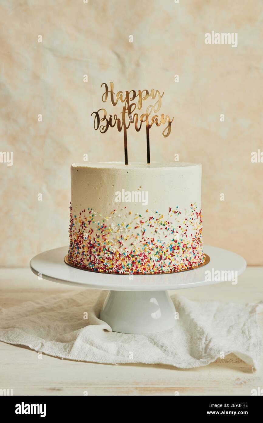 Vertical shot of a cake with a ''happy birthday'' cake topper and ...