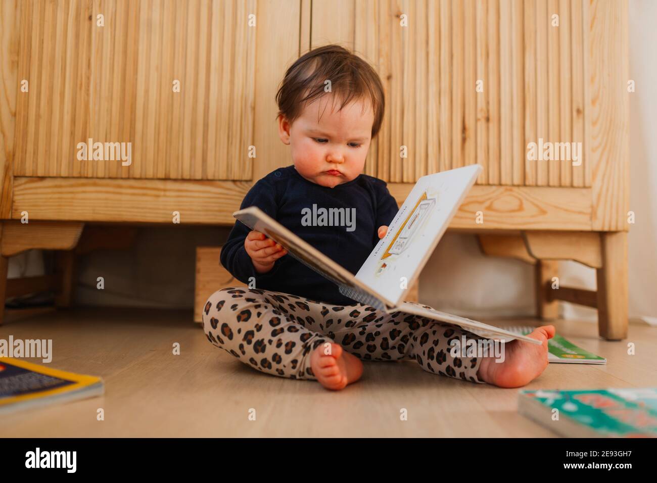 Toddler girl reading book Stock Photo - Alamy