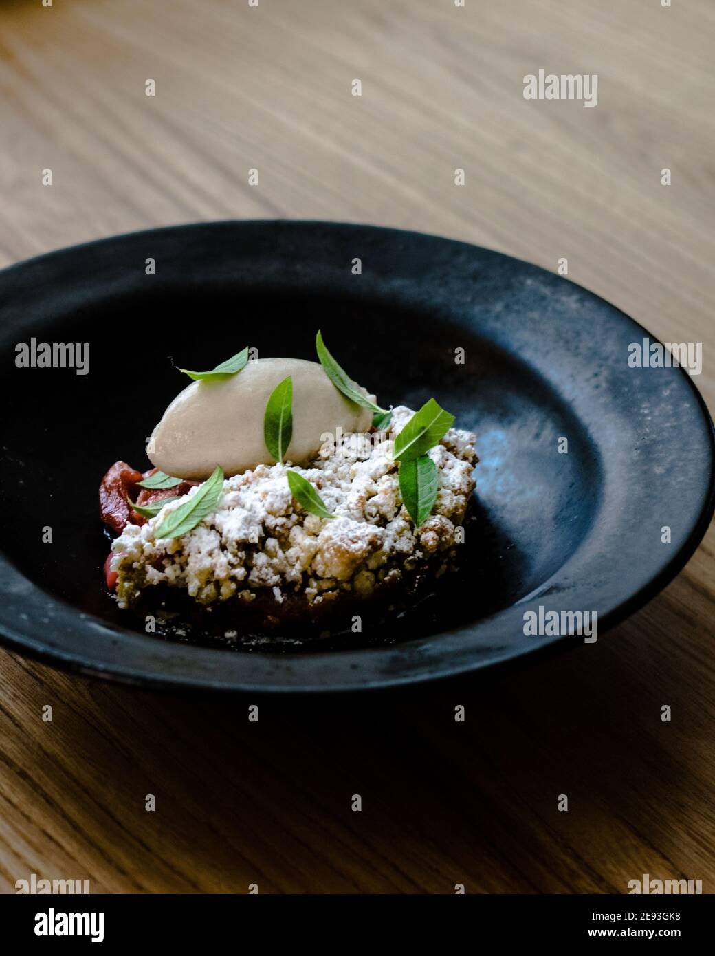 Plate of sorbet and rhubarb pie covered with mint leaves in a black ...