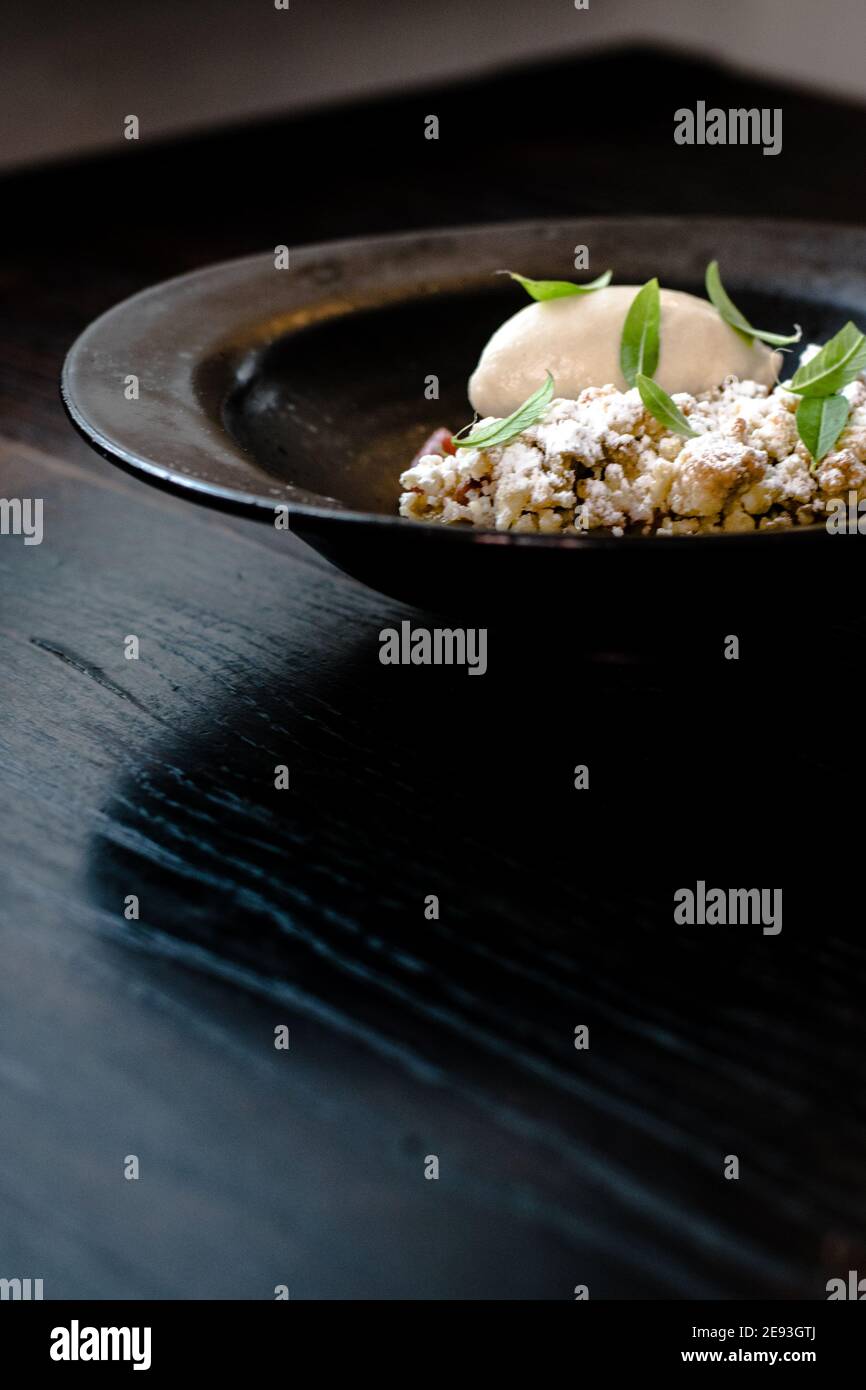 Plate of sorbet and rhubarb pie covered with mint leaves in a black ...