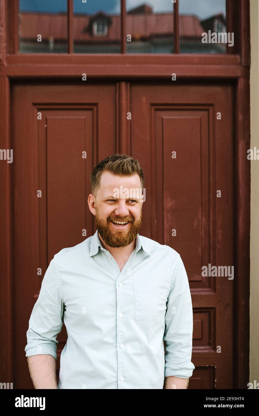 Smiling man standing against door Stock Photo - Alamy