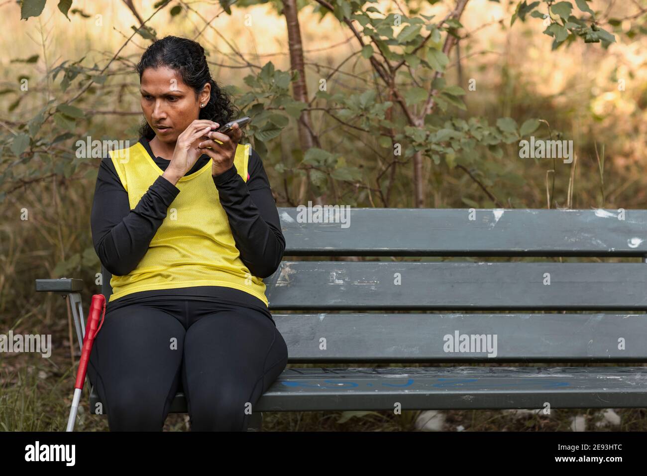 Visually impaired woman sitting on bench and using cell phone Stock ...