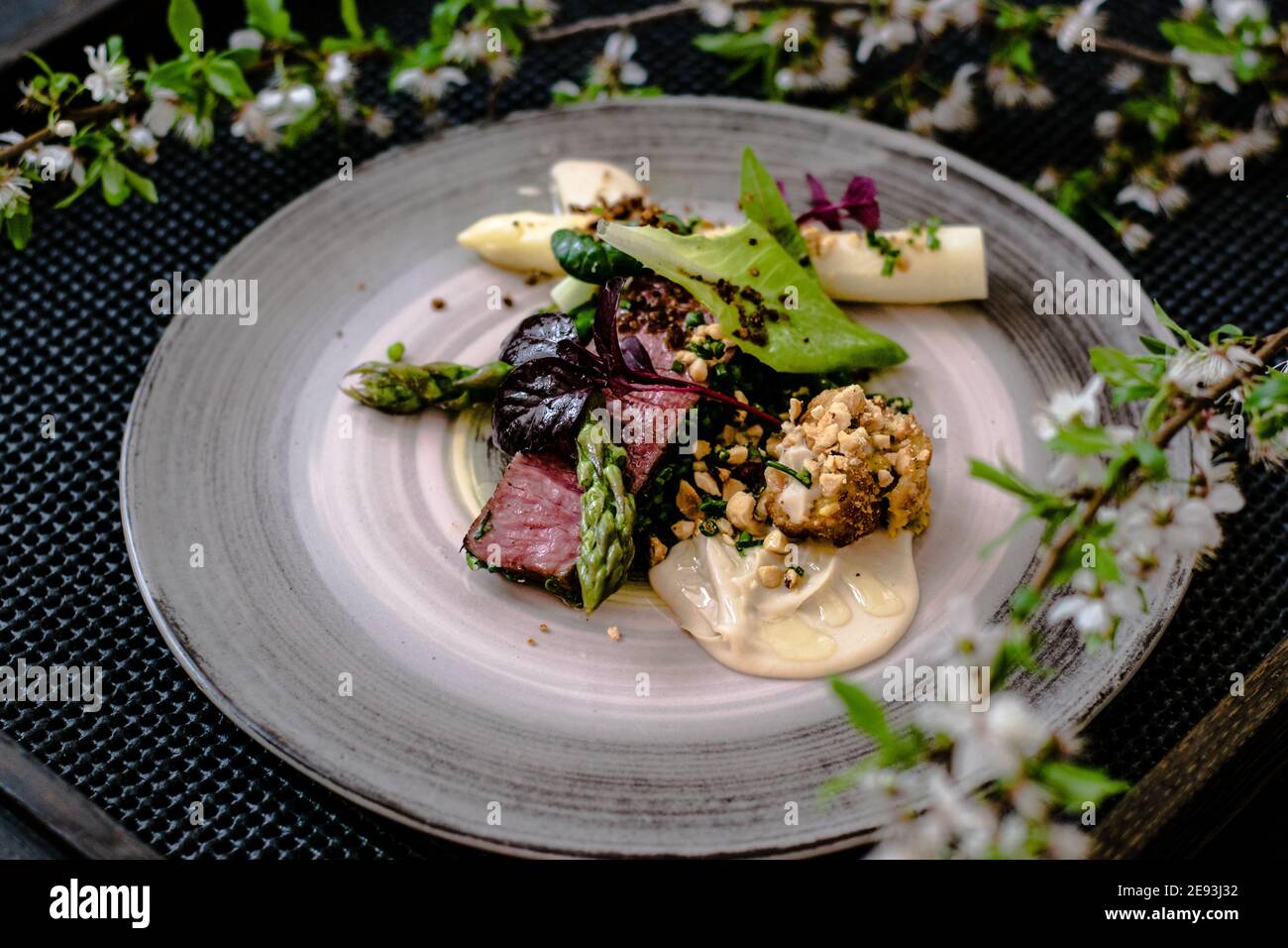 Dish of ostrich steak with white and green asparagus, garden greens and ...