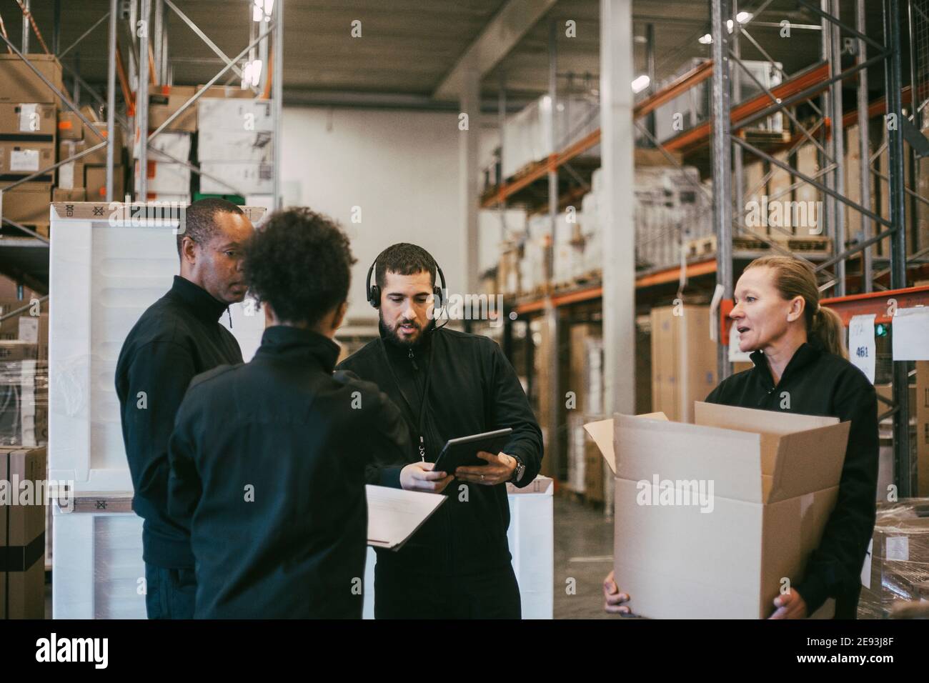 Male and female manual workers discussing during meeting in logistics ...