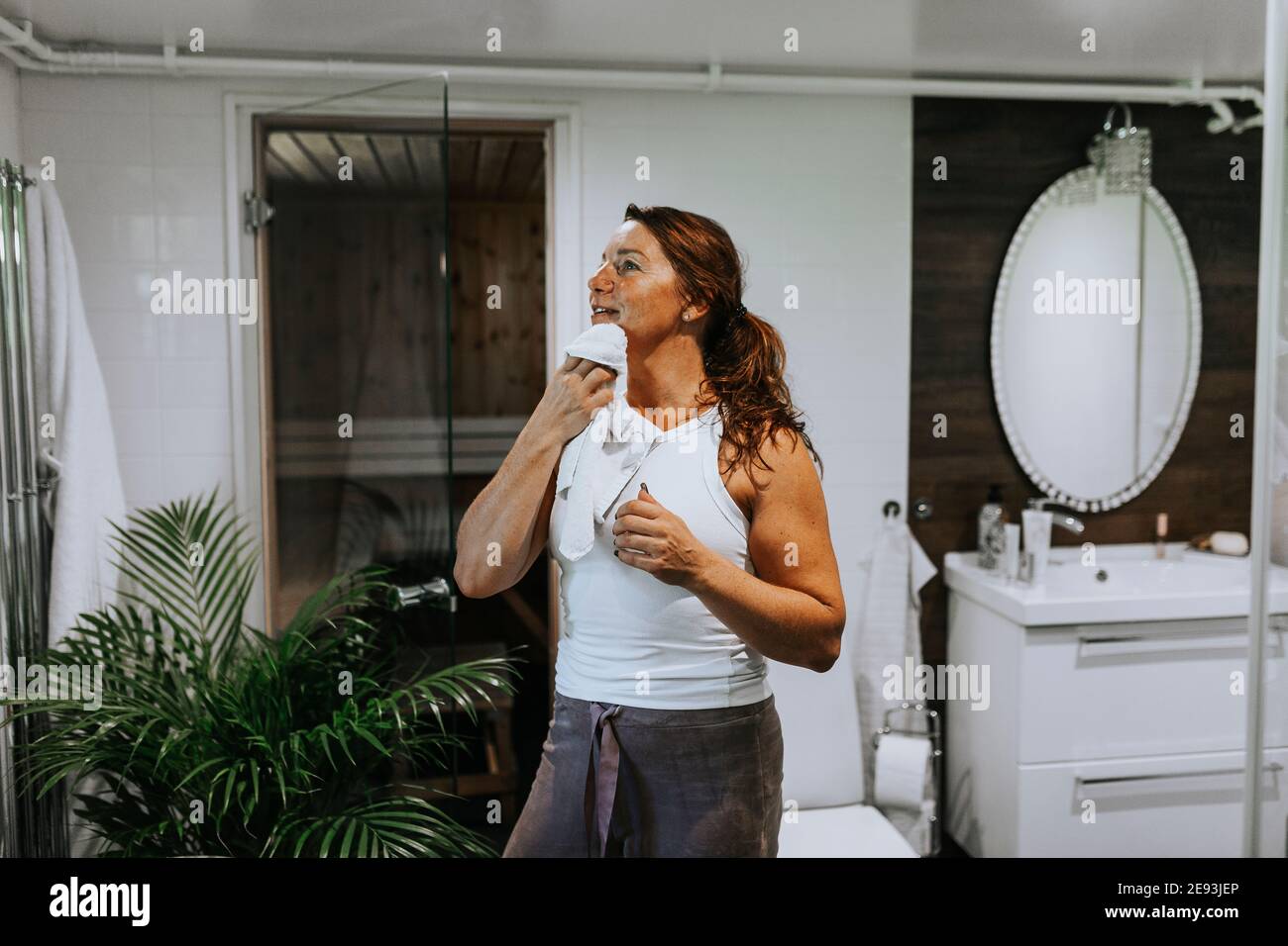 Woman drying face in bathroom Stock Photo - Alamy