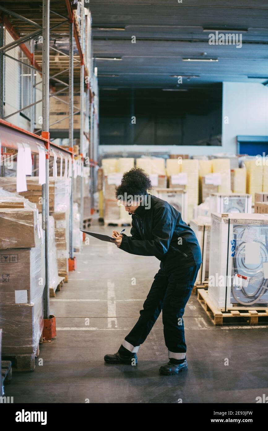 Female manual worker analyzing box containers at distribution warehouse ...