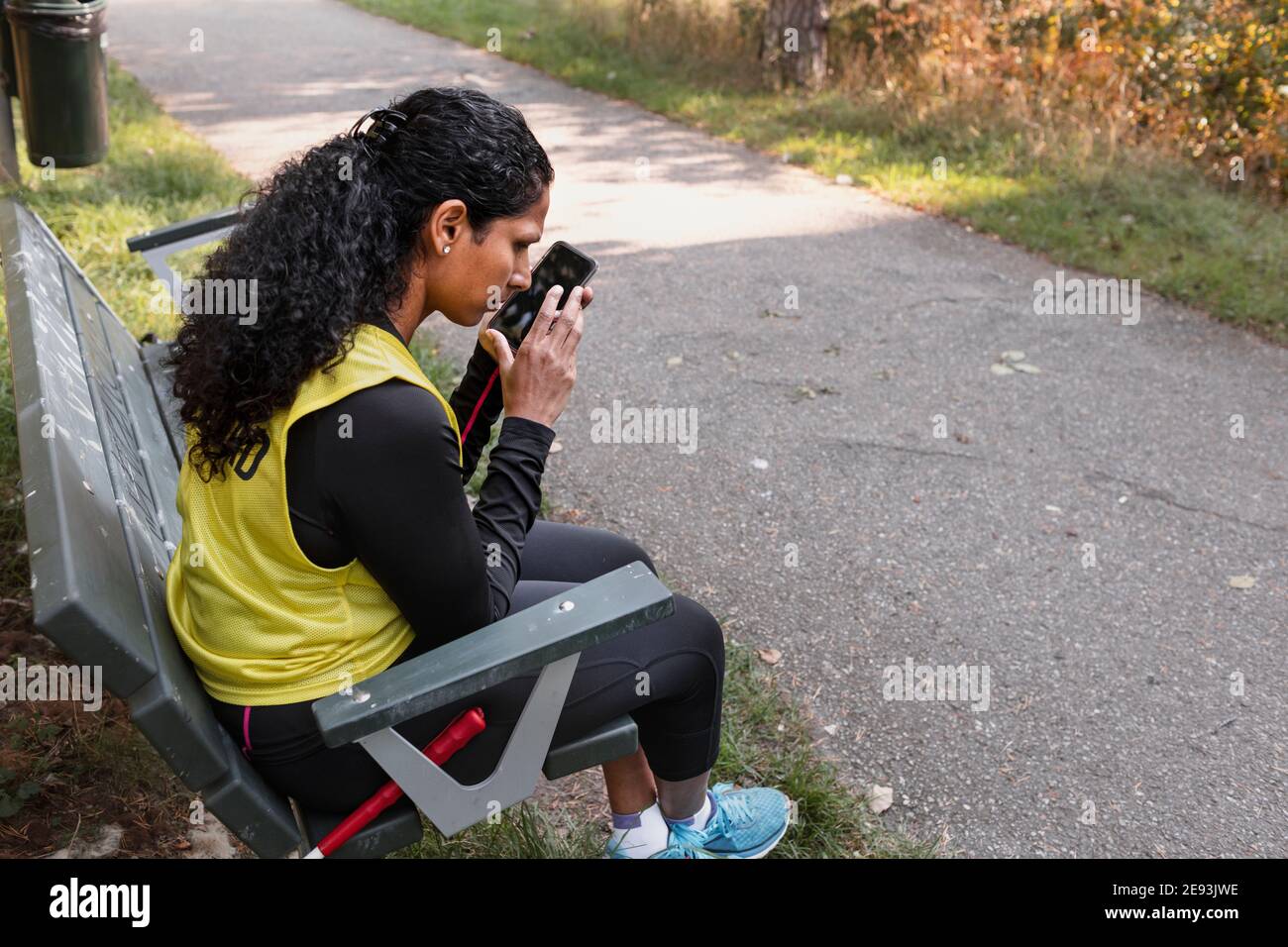 Visually impaired woman sitting on bench and using cell phone Stock ...