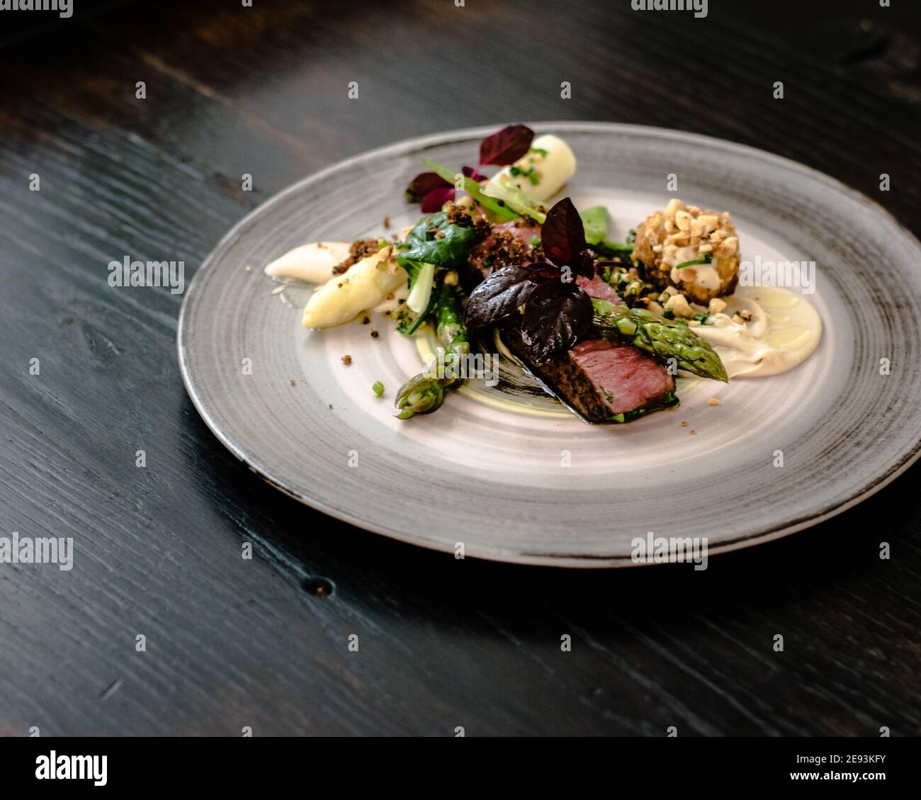 Dish of ostrich steak with white and green asparagus, garden greens and ...