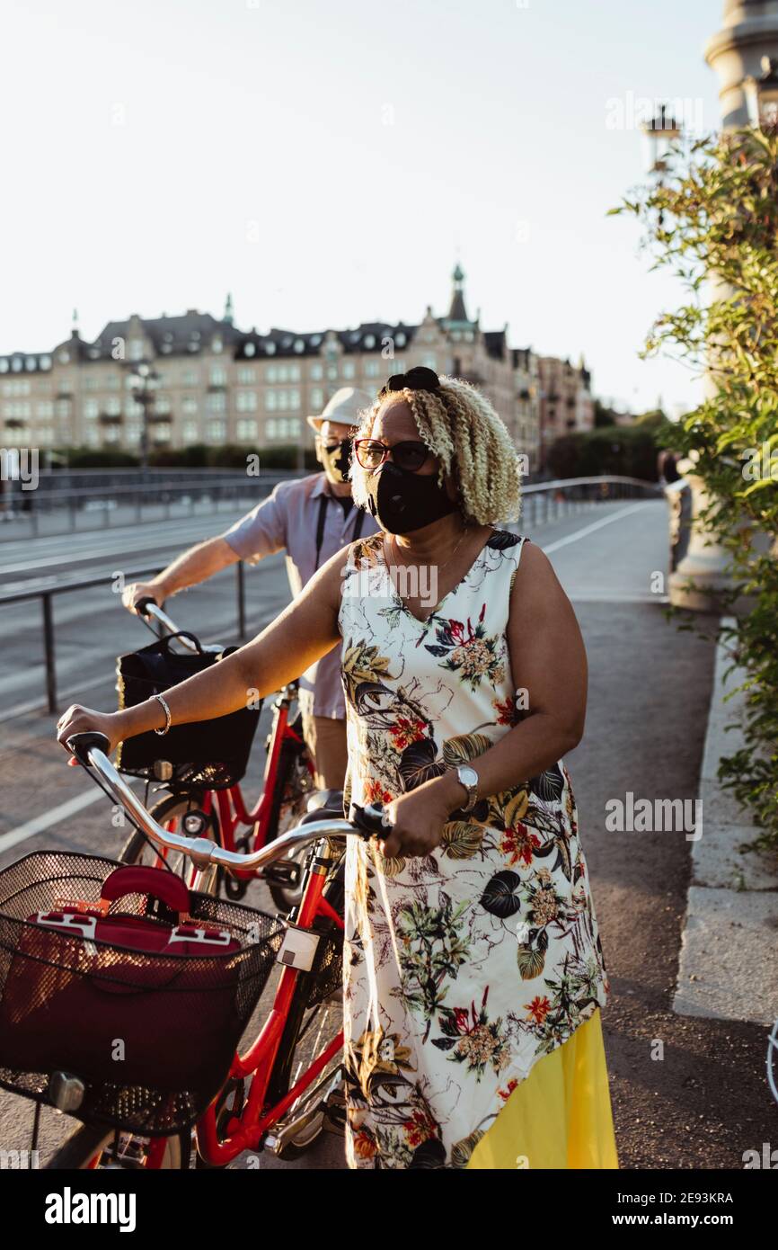 Senior man and woman wheeling bicycle on bridge during pandemic Stock ...
