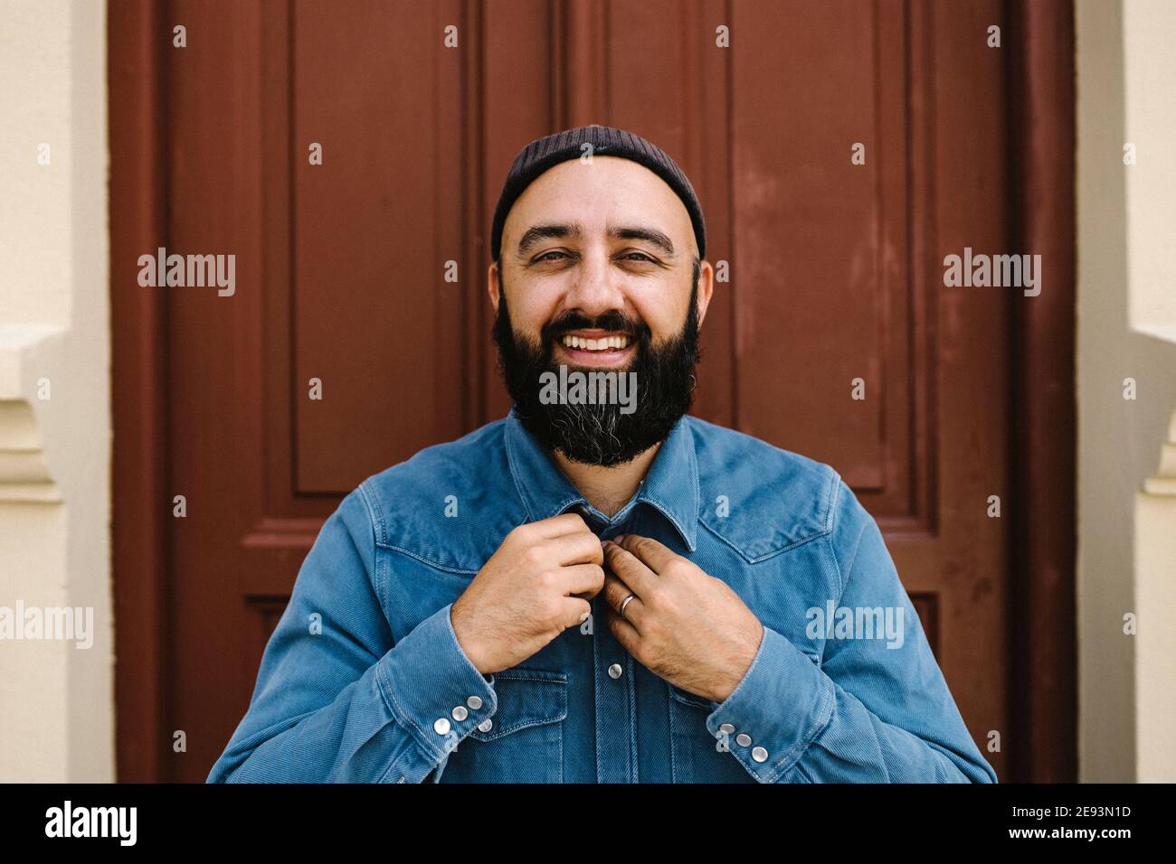 Smiling man standing against door Stock Photo - Alamy