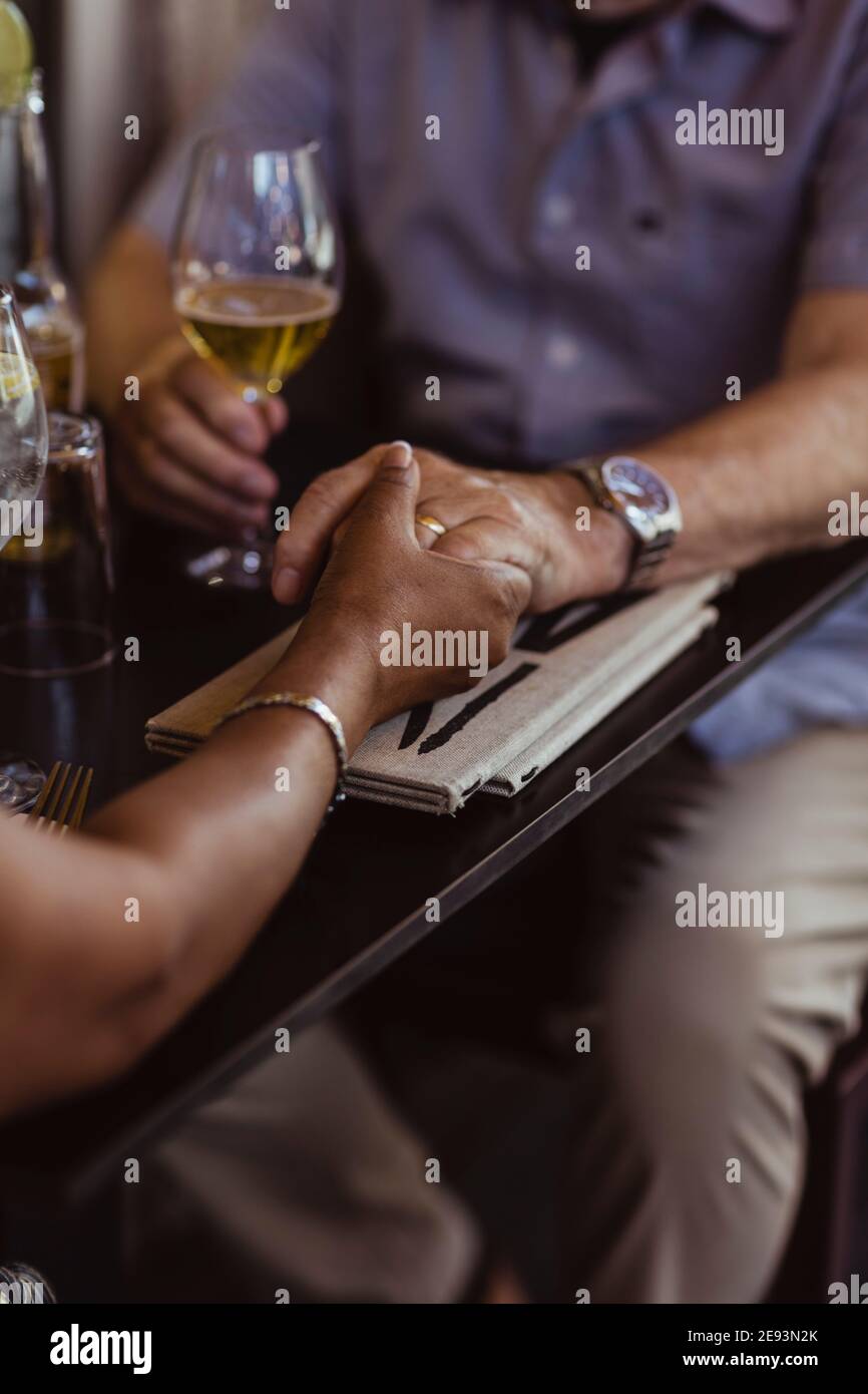 Cropped image of couple holding hands over table in cafe Stock Photo ...