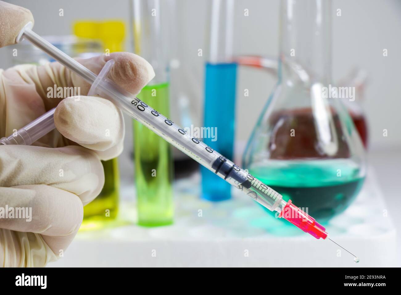 Hand in glove holding syringe with liquid insulin with chemical ...