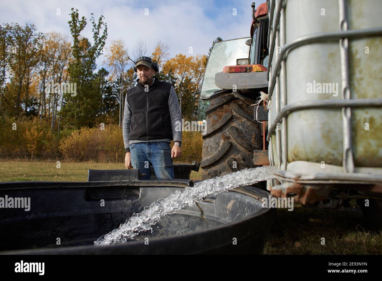 Farmer pouring water for animals Stock Photo - Alamy