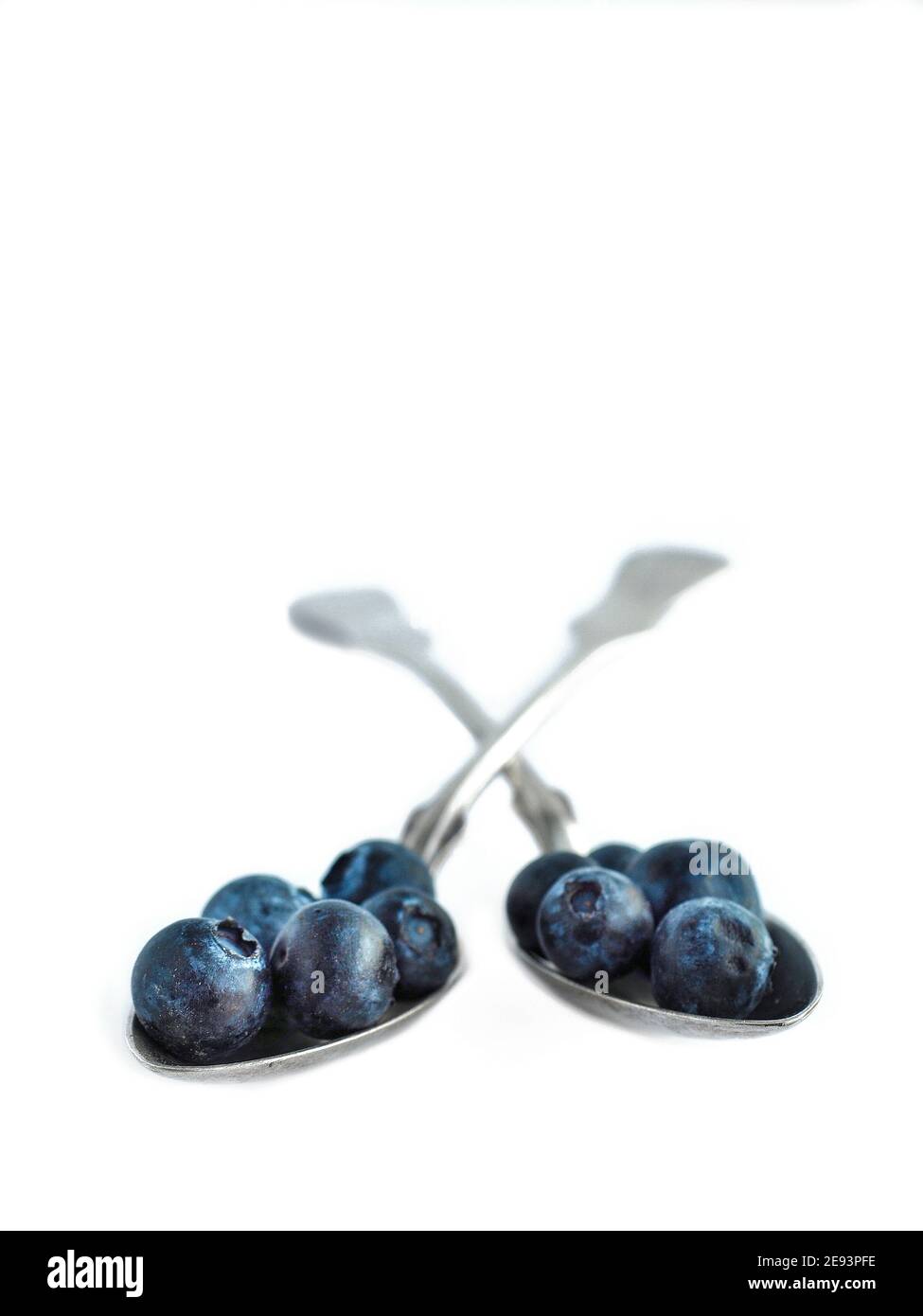 Two crossed vintage spoons with fresh blueberries isolated on white ...